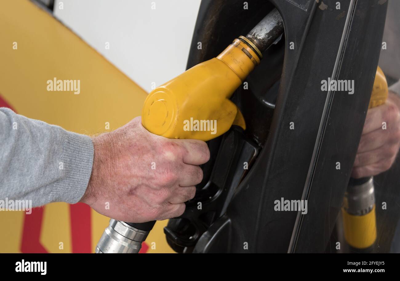 Man holding a yellow fuel pump nozzle Stock Photo - Alamy