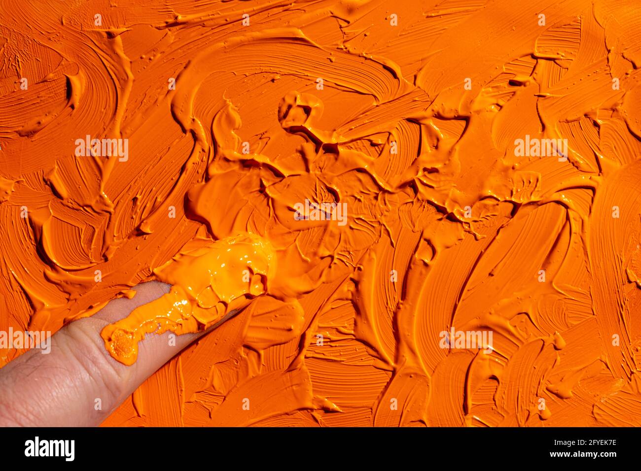 spread a patch of orange acrylic color with your finger Stock Photo - Alamy