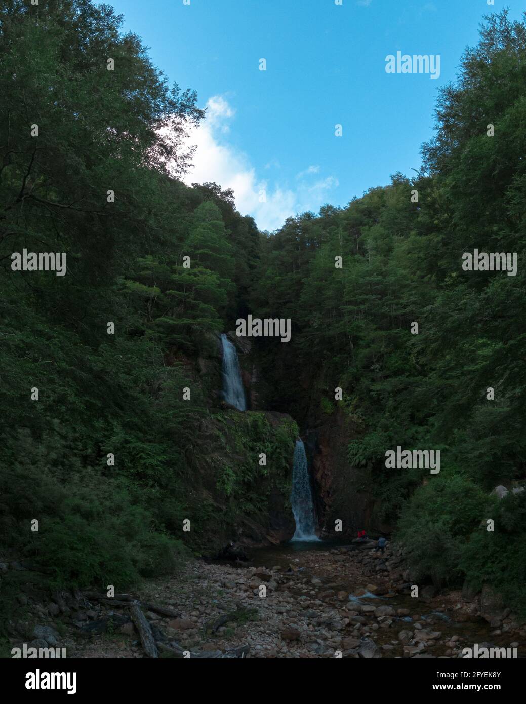 Vertical shot of waterfall with double fall on the side of the road ...