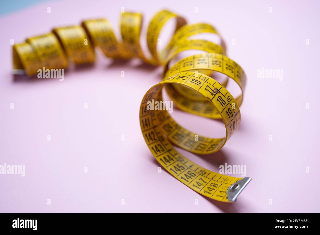 a tape measure rolled up on a colored surface Stock Photo - Alamy
