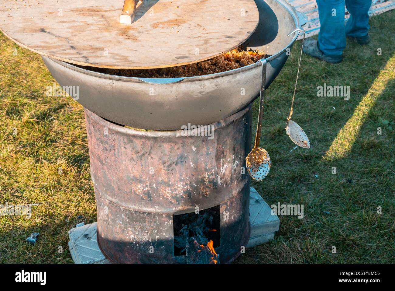 Hot pilaf in a large cauldron on the stove in the park. Traditional ...