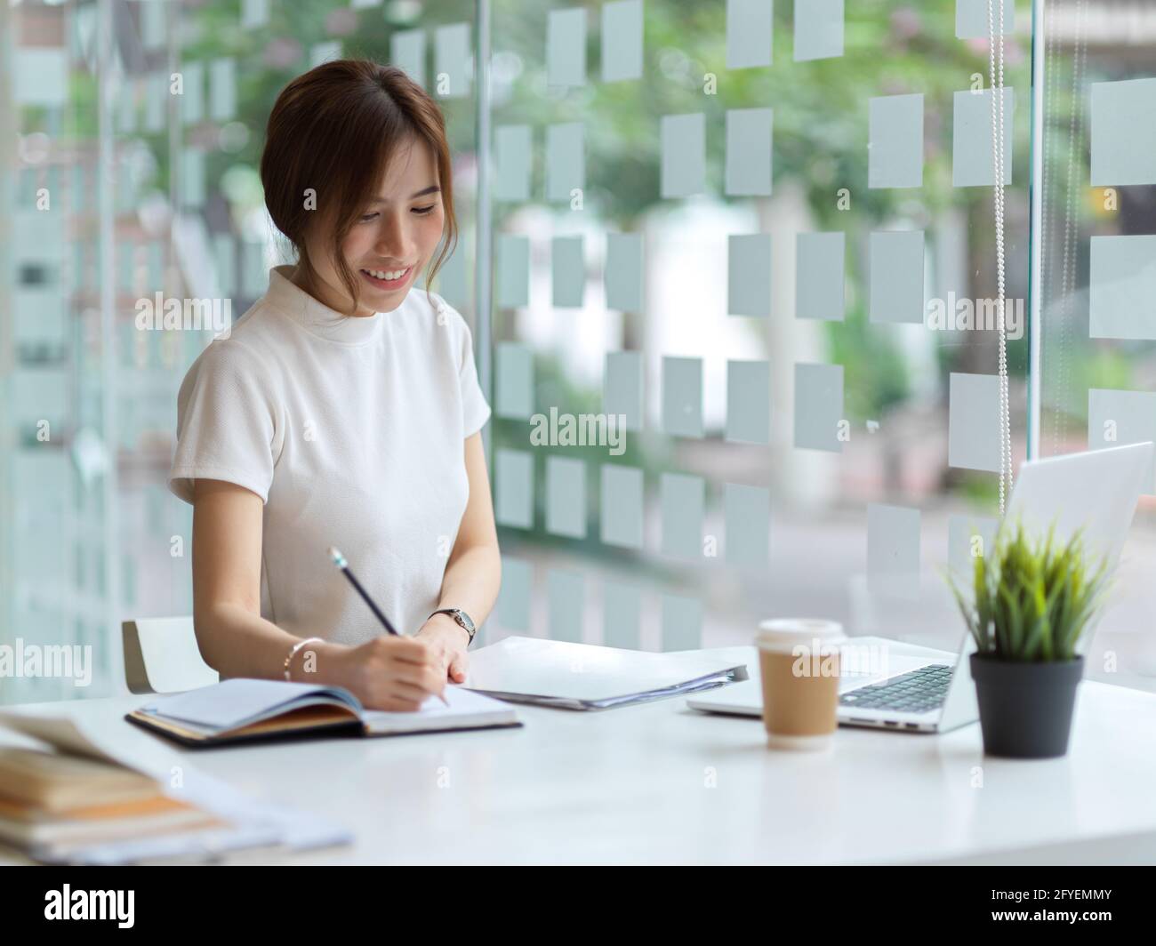 Cropped shot of female student doing assignment, writing on notebook in ...