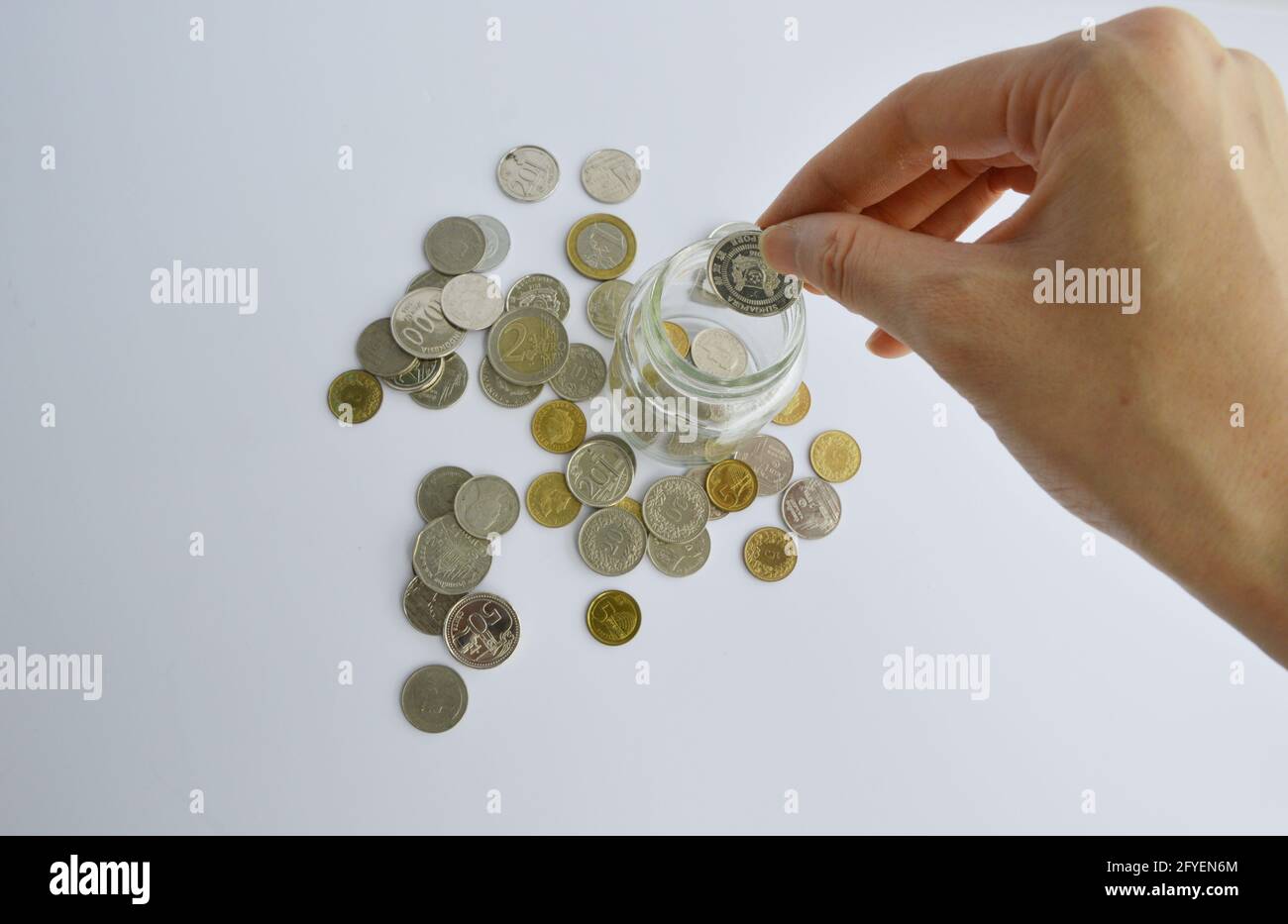 Hand putting coins in jar hi-res stock photography and images - Alamy