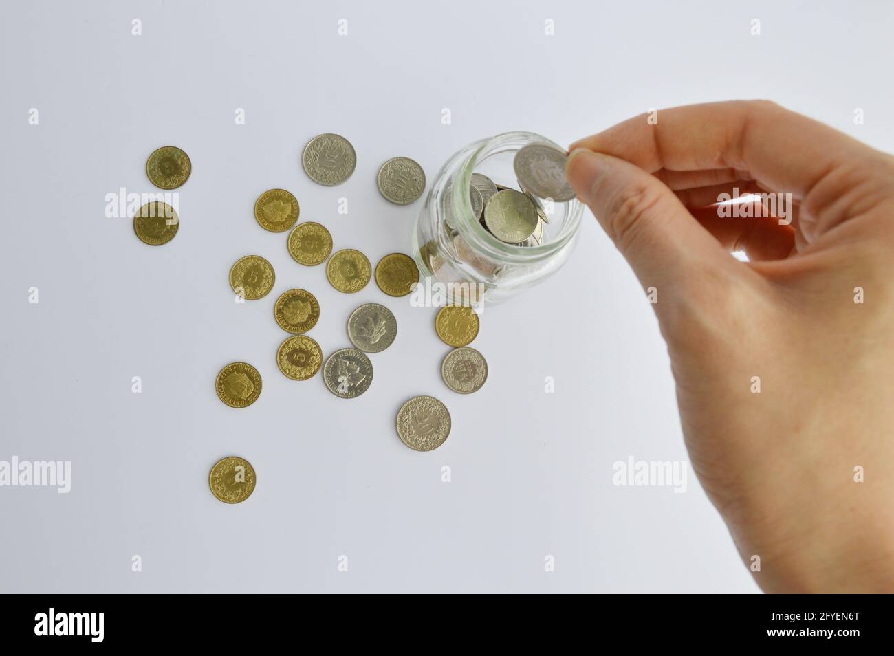 Hand putting coins in jar hi-res stock photography and images - Alamy