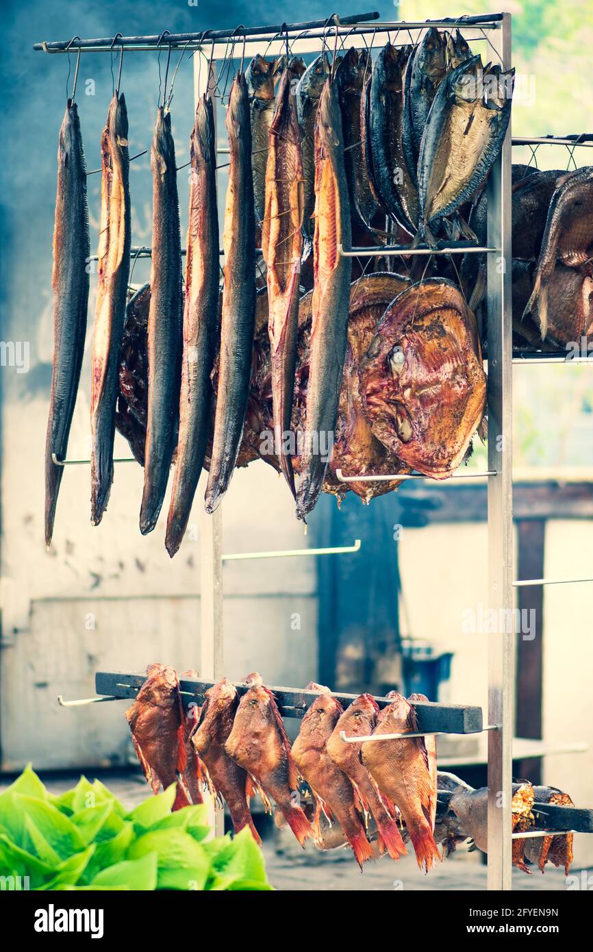 Various dry smoked spiced fish with smoke on background ready to eat in ...