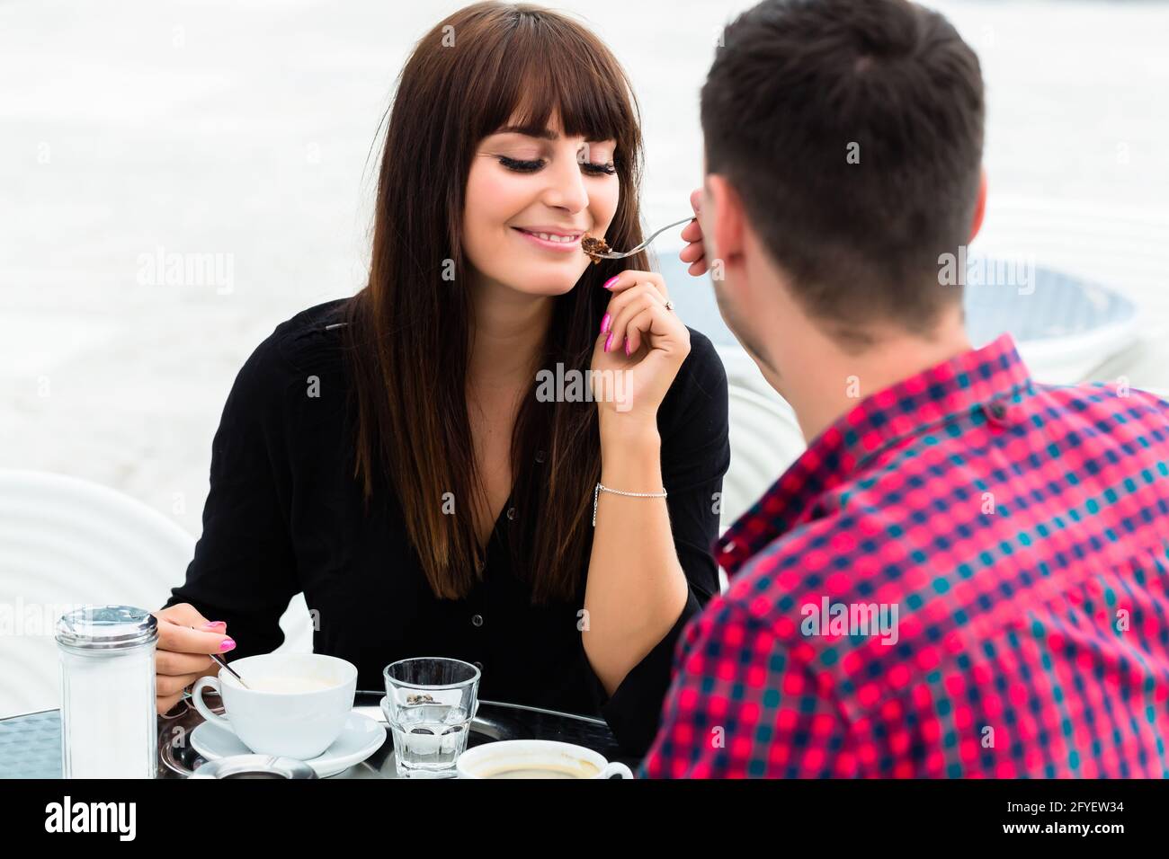 Rear view of a man feeding his girlfriend with spoon at cafe Stock ...