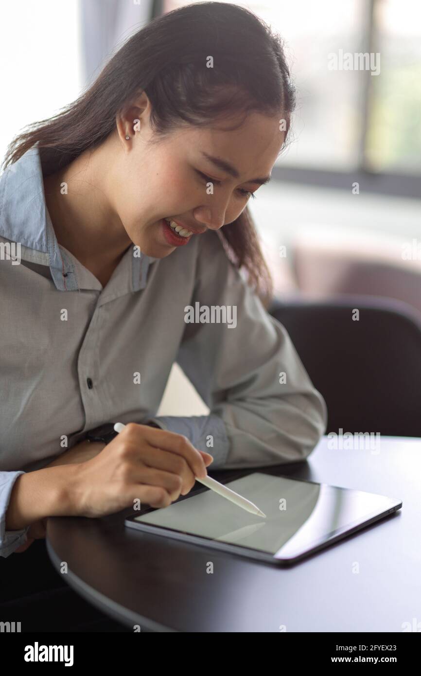 Young female writing on mock up blank screen digital tablet while ...