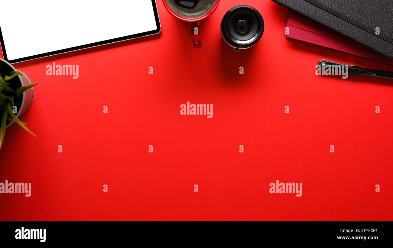 Top view of working table with tablet and office supplies on bright red ...