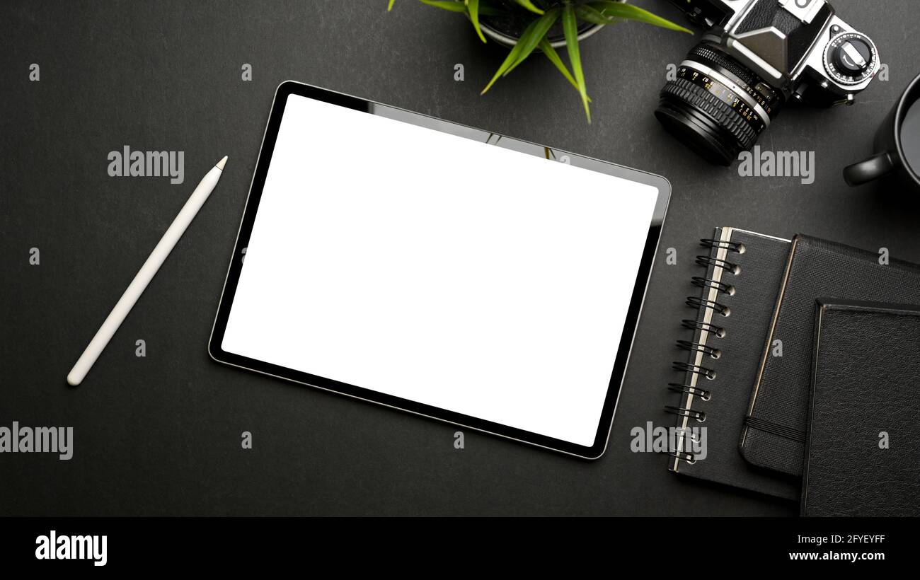 Dark creative workspace with digital tablet, camera, stationery and ...