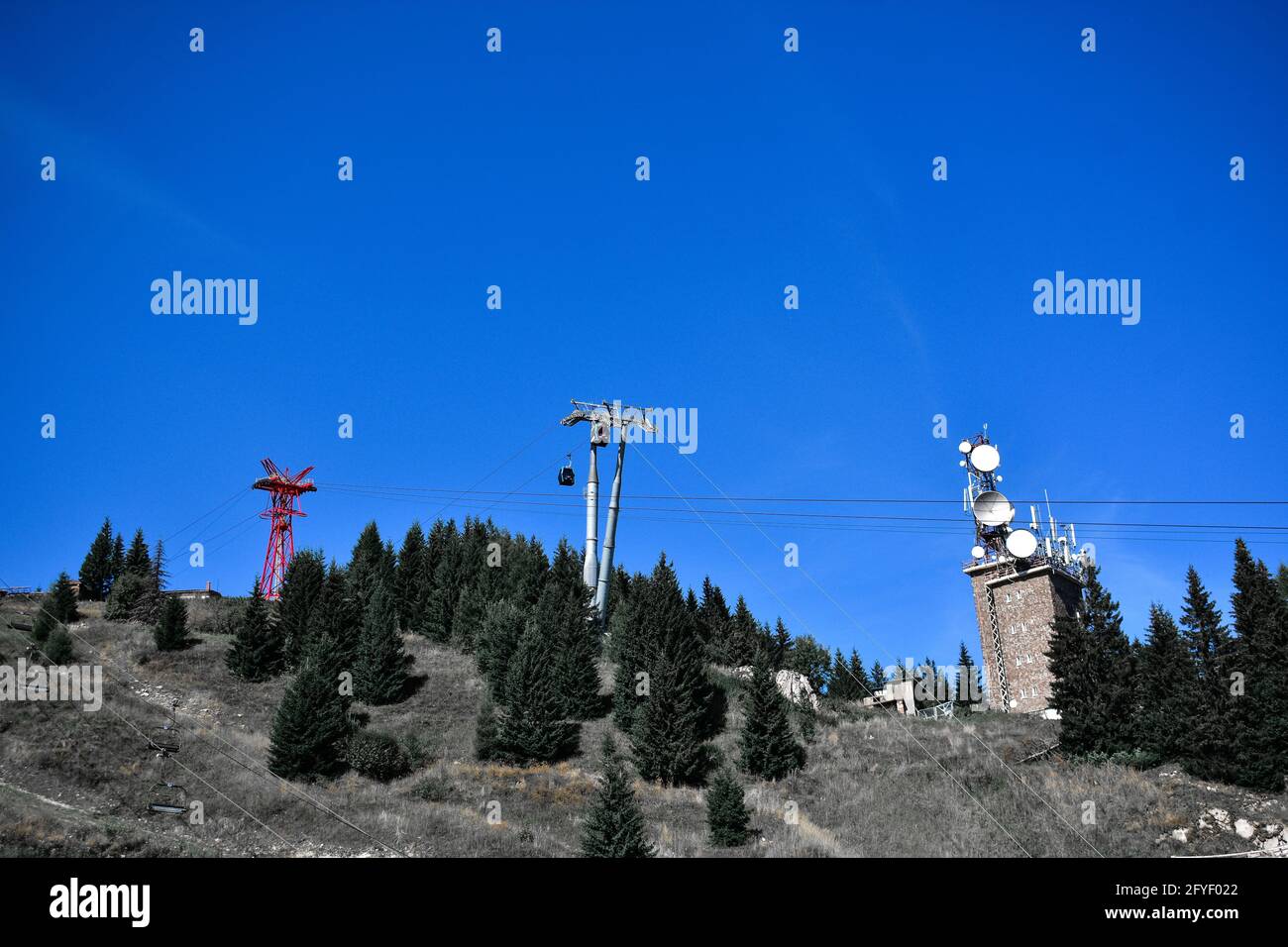 Low angle shot of transmission lines and radio tower with trees on a ...