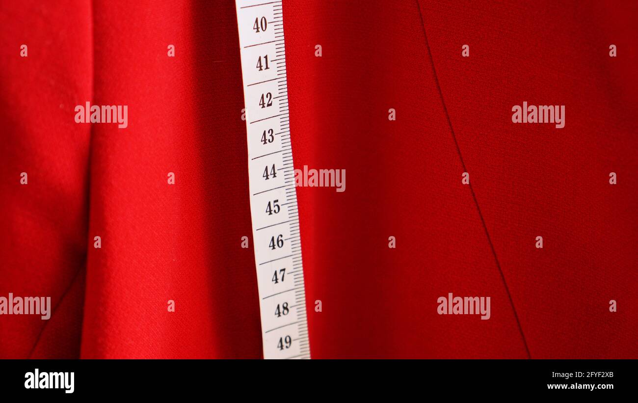 White measuring tape on the background of the red fabric of the jacket ...