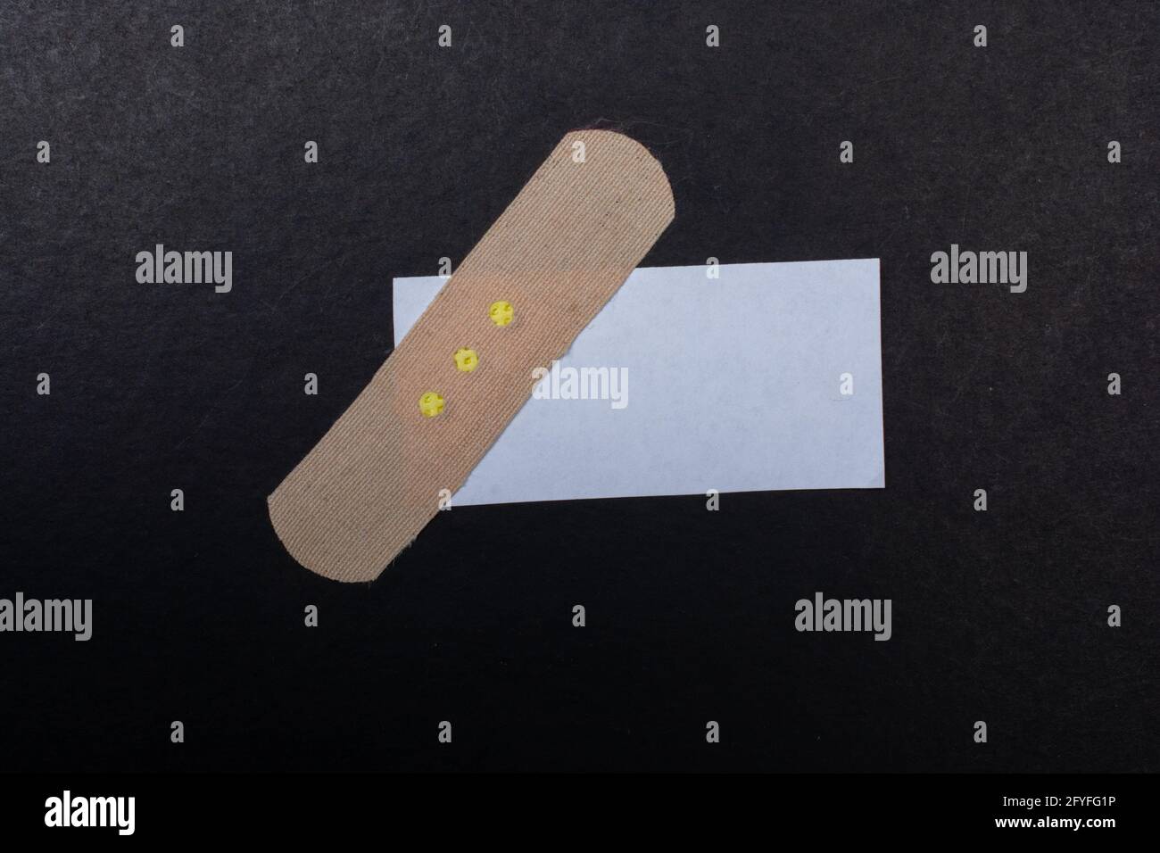 Closeup shot of a paper and an adhesive bandage on a black background ...