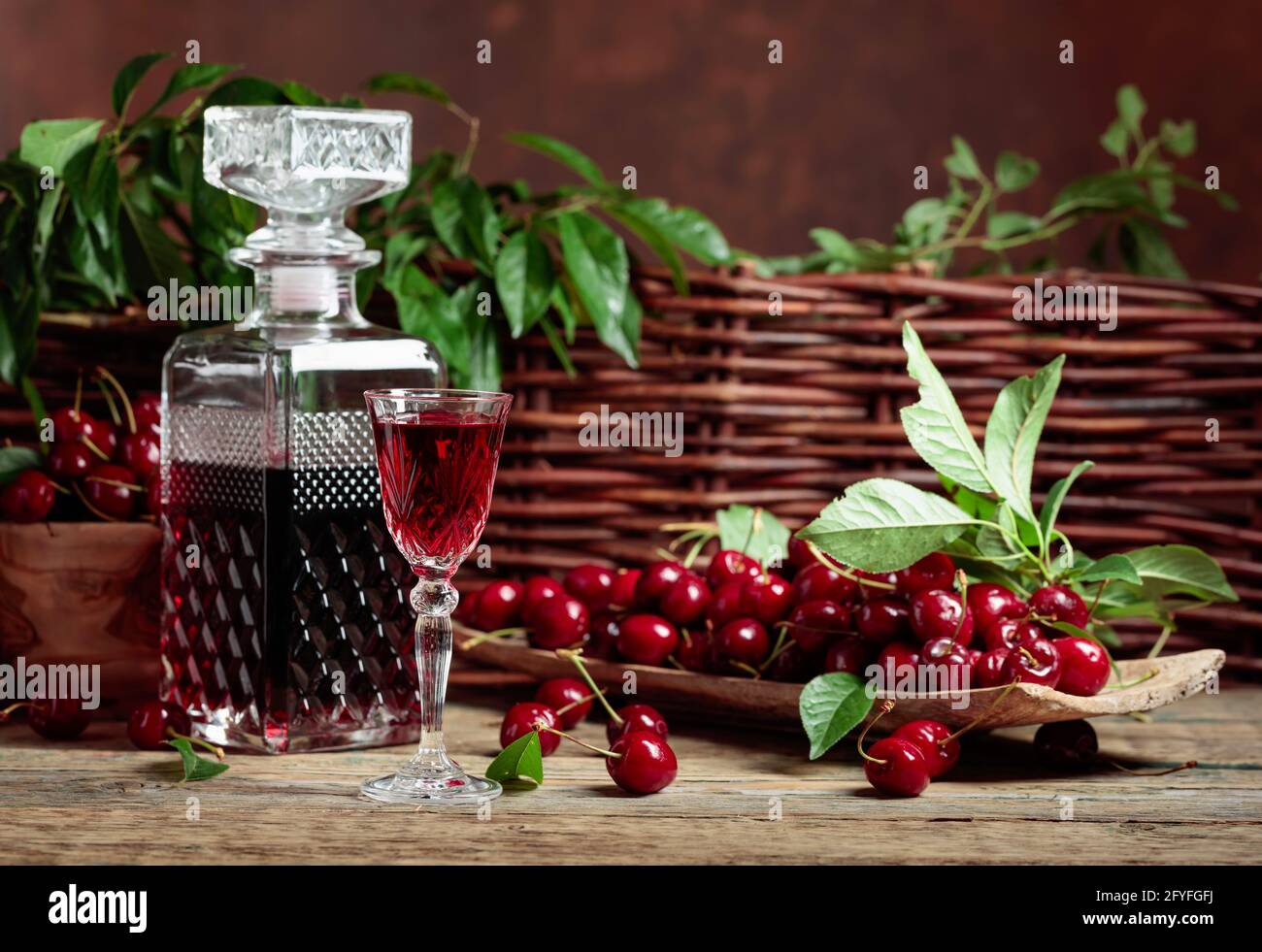 Cherry liquor and red cherries in a wooden bowl on a wooden table in ...