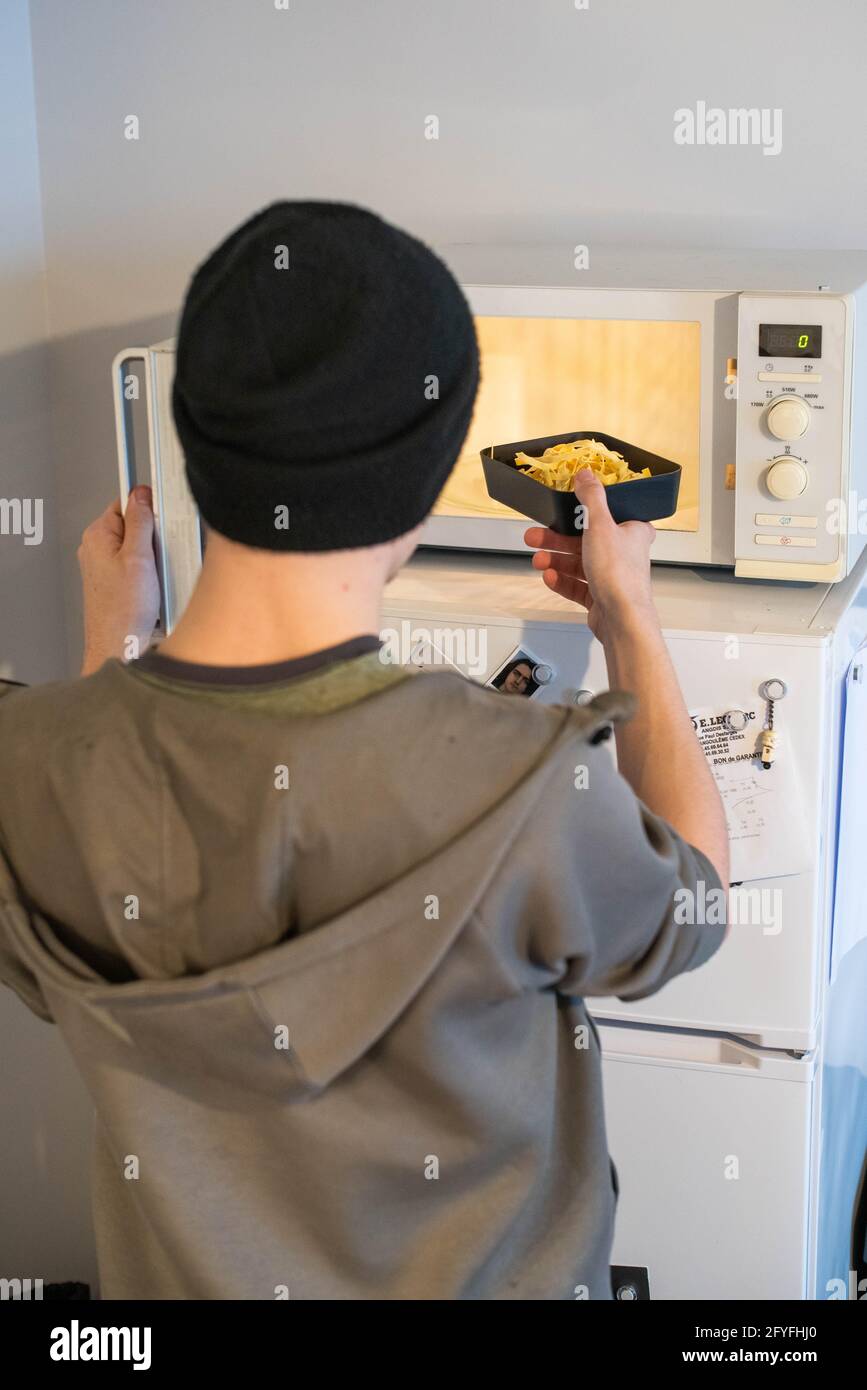 Young man using a microwave oven, France Stock Photo - Alamy
