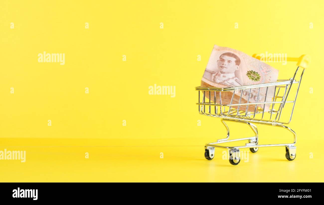 Shopping cart and one thousand Thai baht note on a yellow background ...