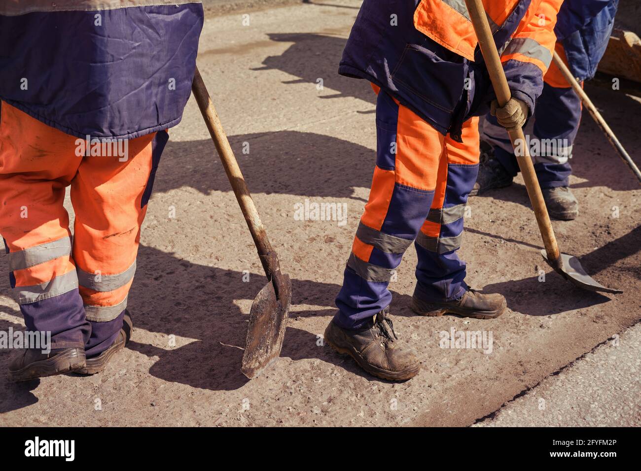 Road workers in uniform with shovels change the asphalt Stock Photo - Alamy