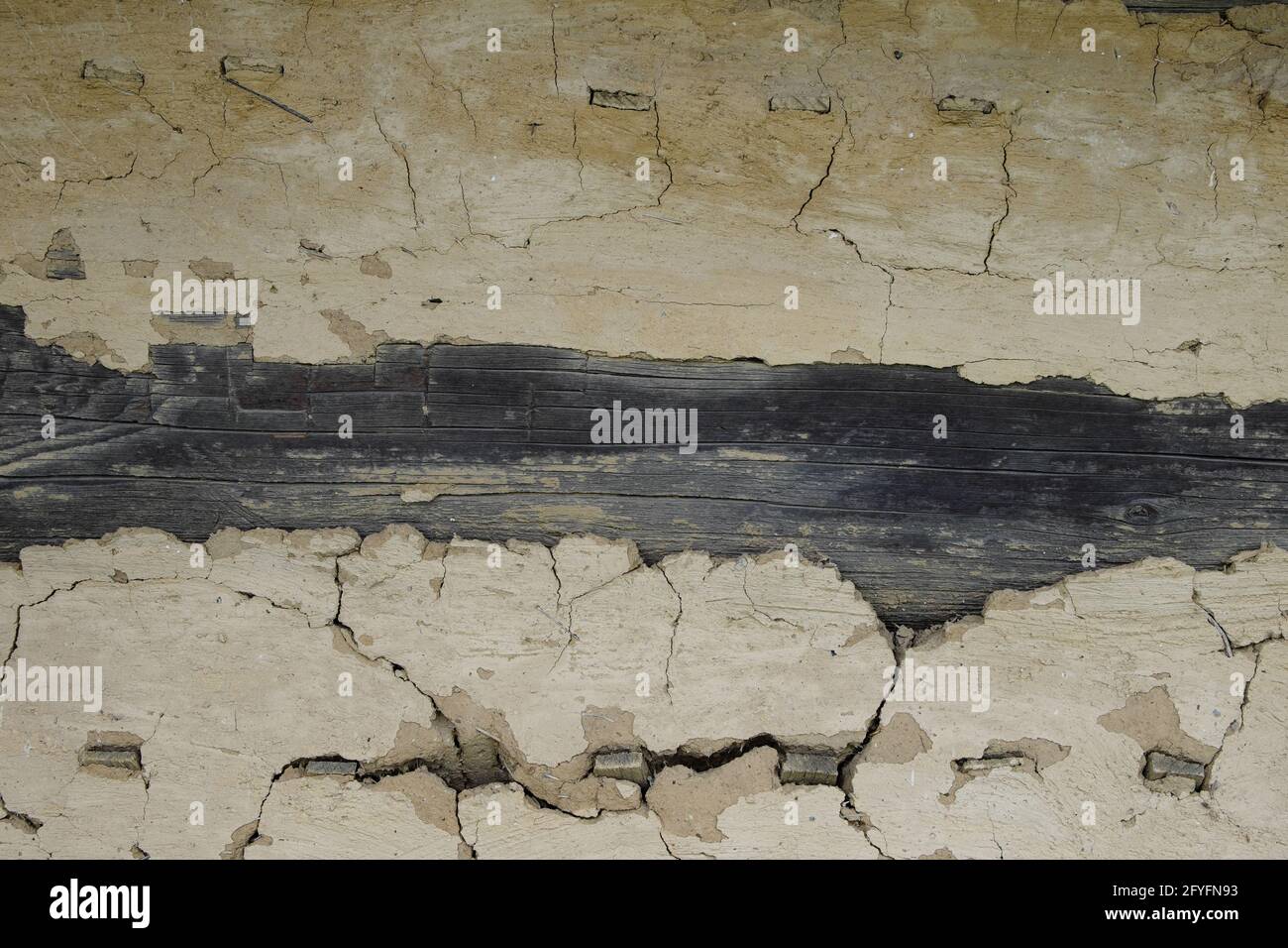 A fragment of the old wall of a log house with clay-covered cracks ...