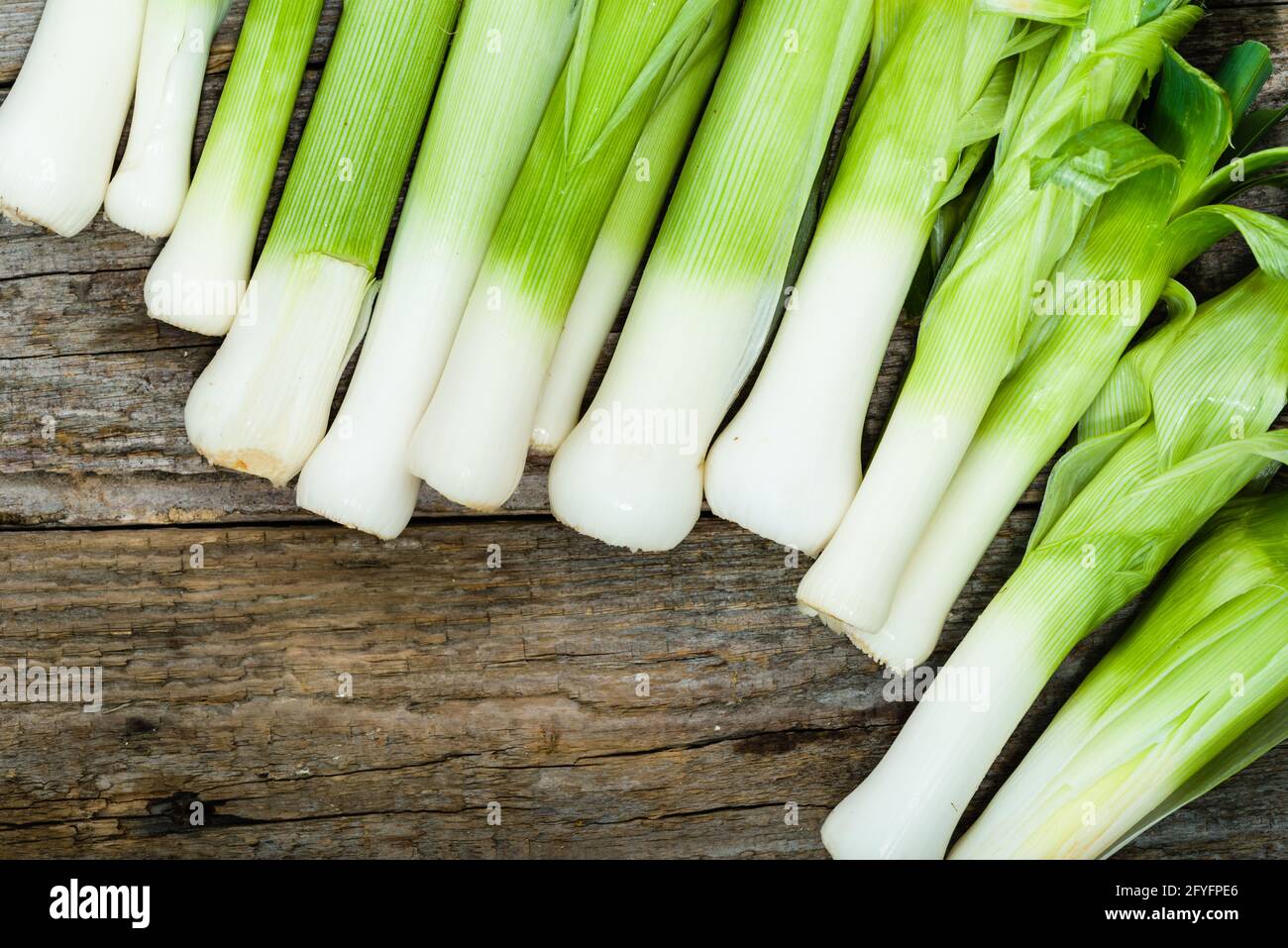 Stalks of leeks, green vegetables, local market produce on rustic ...