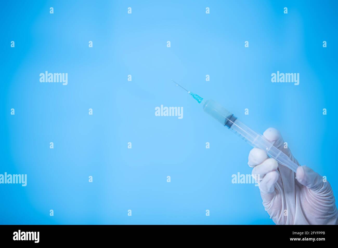 Close-Up Of Syringe Against blurred of doctor face blue Background ...