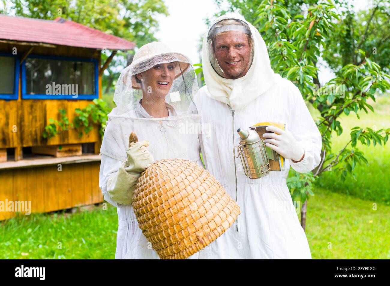 Beekeeper team working outdoor with smoker and beehive Stock Photo - Alamy