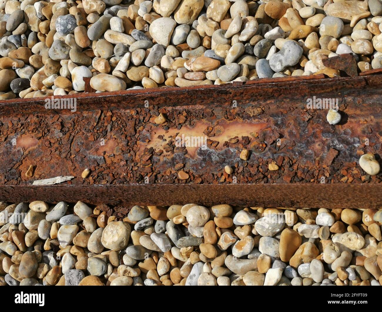 Old corroded rusty metal beam or steel lying across pebble beach Stock ...
