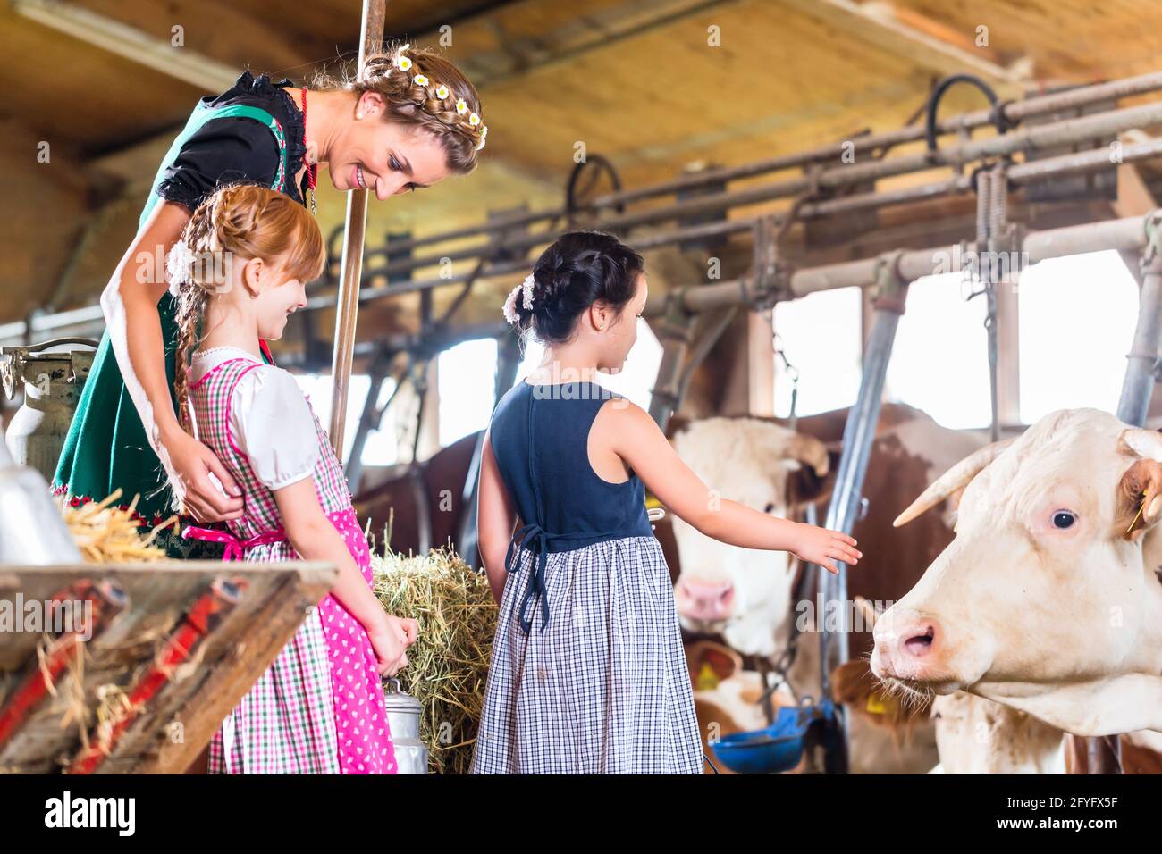 Bavarian mother showing children cows on cow farm Stock Photo - Alamy
