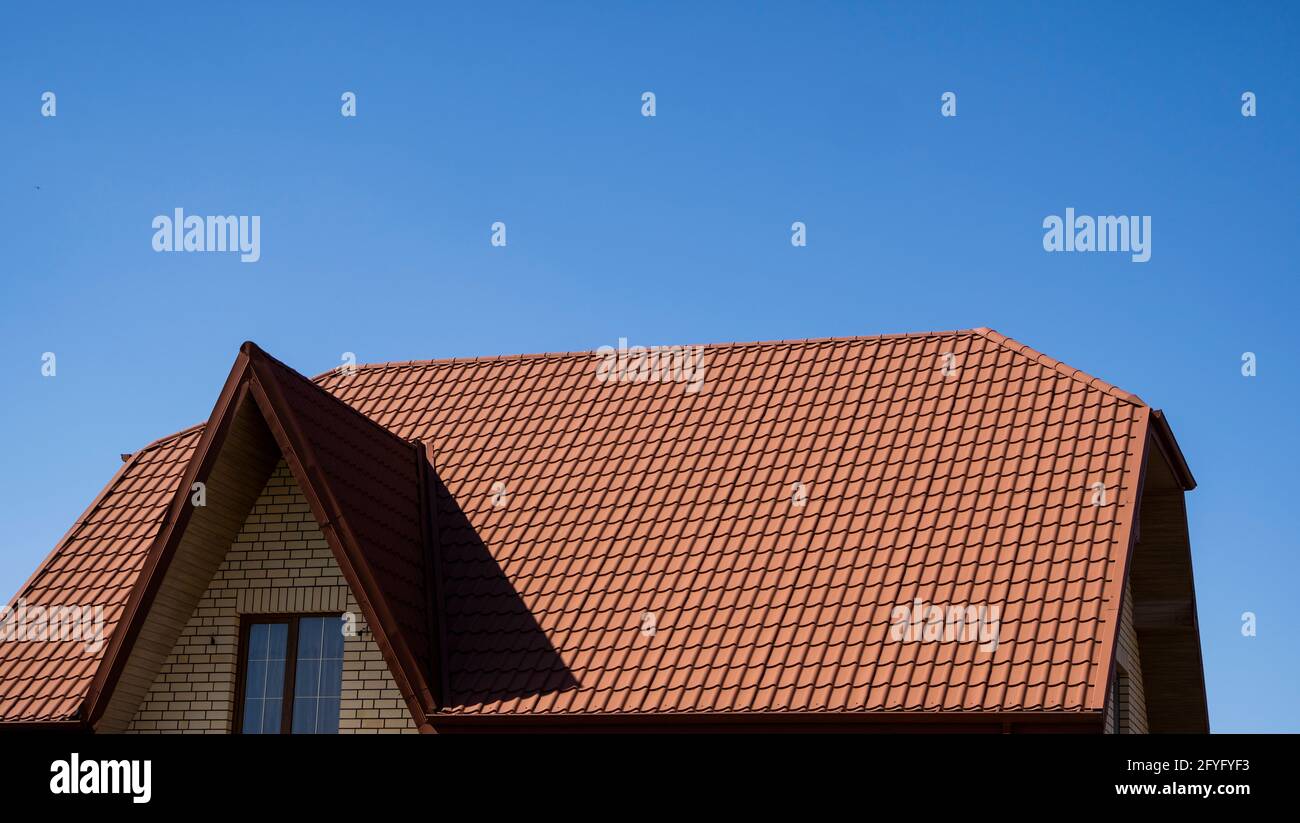 Red corrugated metal profile roof installed on a modern house. The roof ...