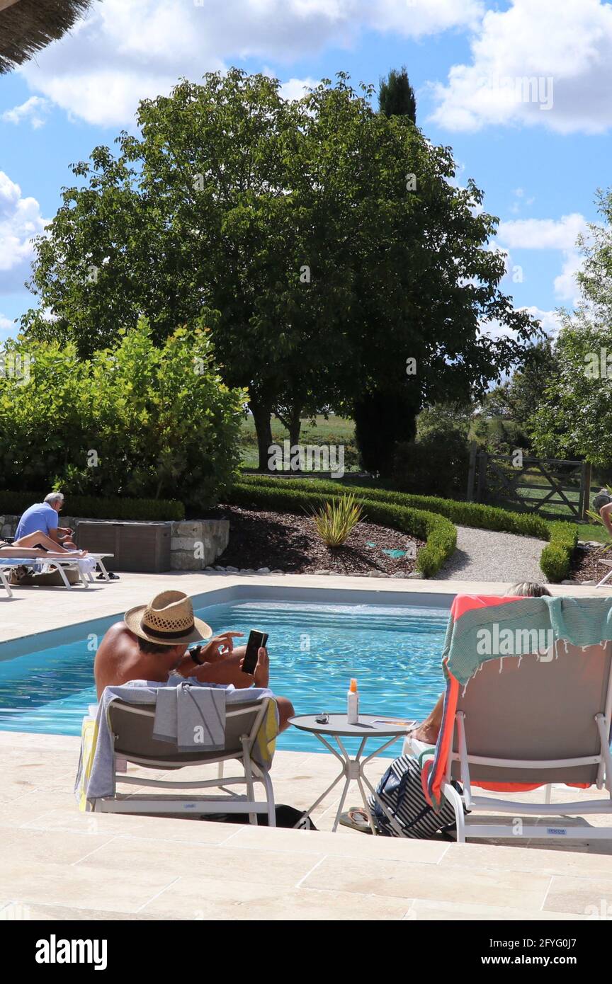 people relaxing in sun chairs next to a pool Stock Photo - Alamy