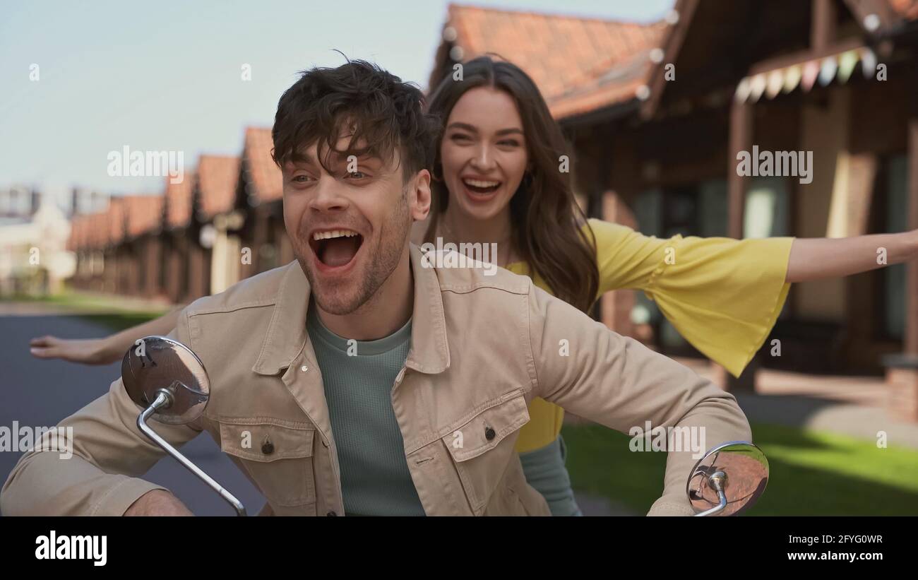 cheerful man riding motorcycle with excited woman Stock Photo - Alamy
