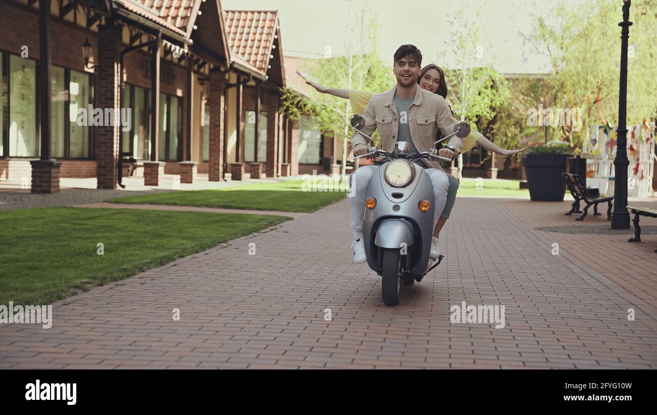joyful man and happy woman with outstretched hands riding motorcycle on ...