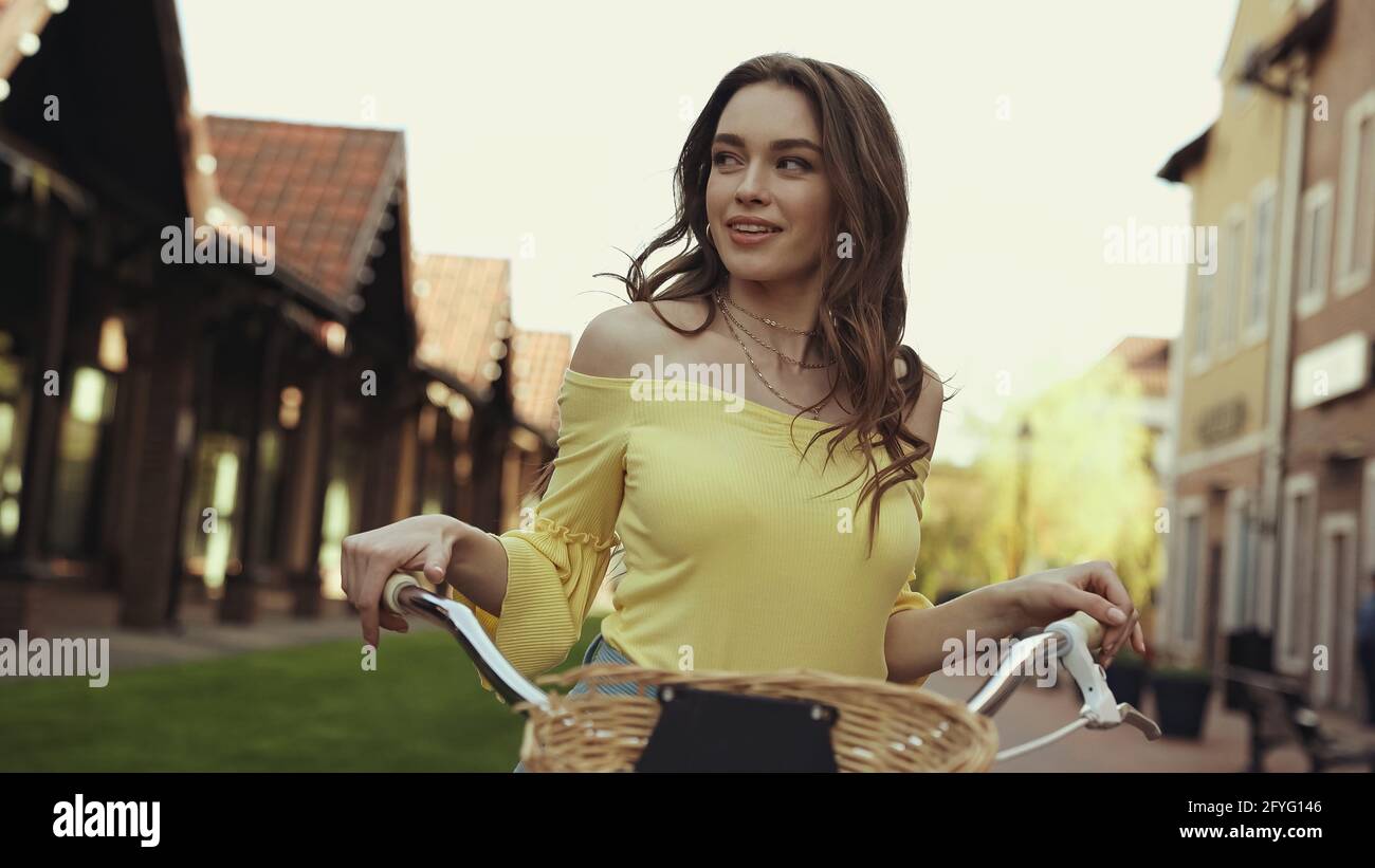 happy young woman with wavy hair riding bike outside Stock Photo - Alamy