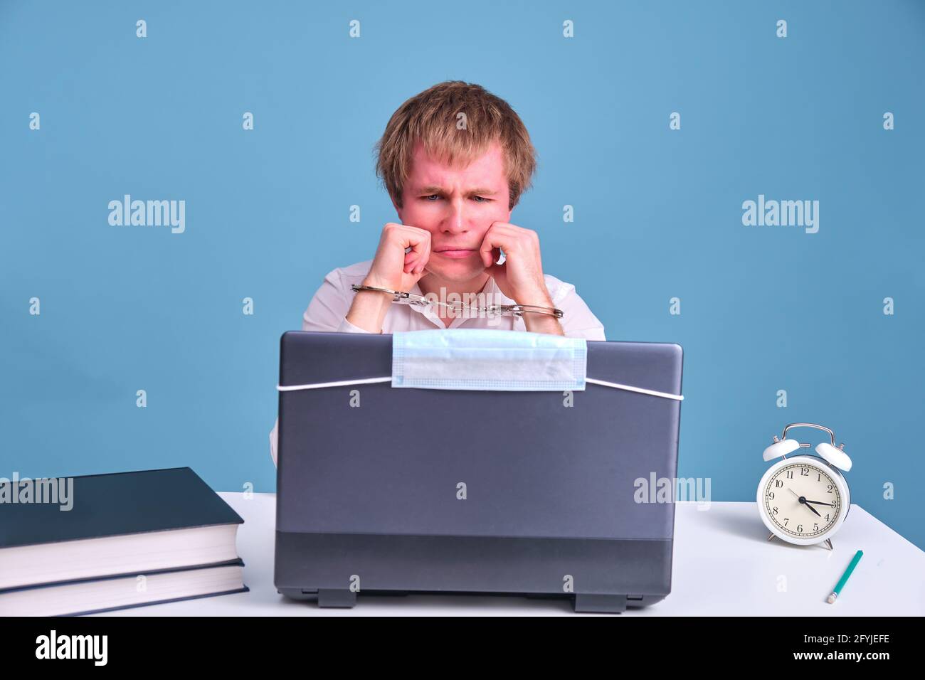 Crying man with computer and handcuffs, studio blue background Stock ...
