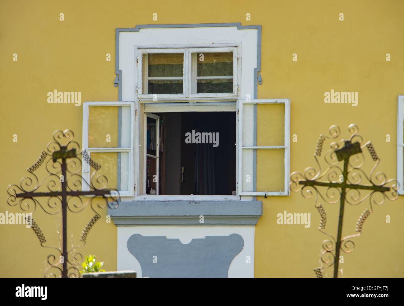Old crosses on graves under the open window of a building with a ...