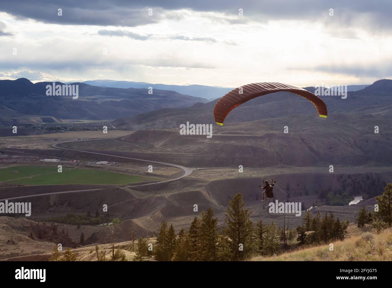 Adventurous Man Flying on a Paraglider around the mountains Stock Photo ...