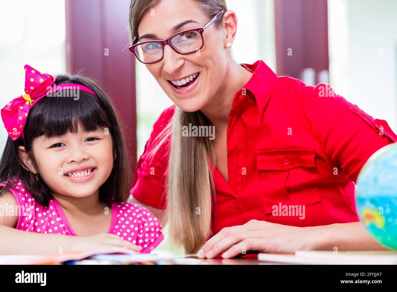 Teacher giving language lessons and doing homework to Chinese child ...