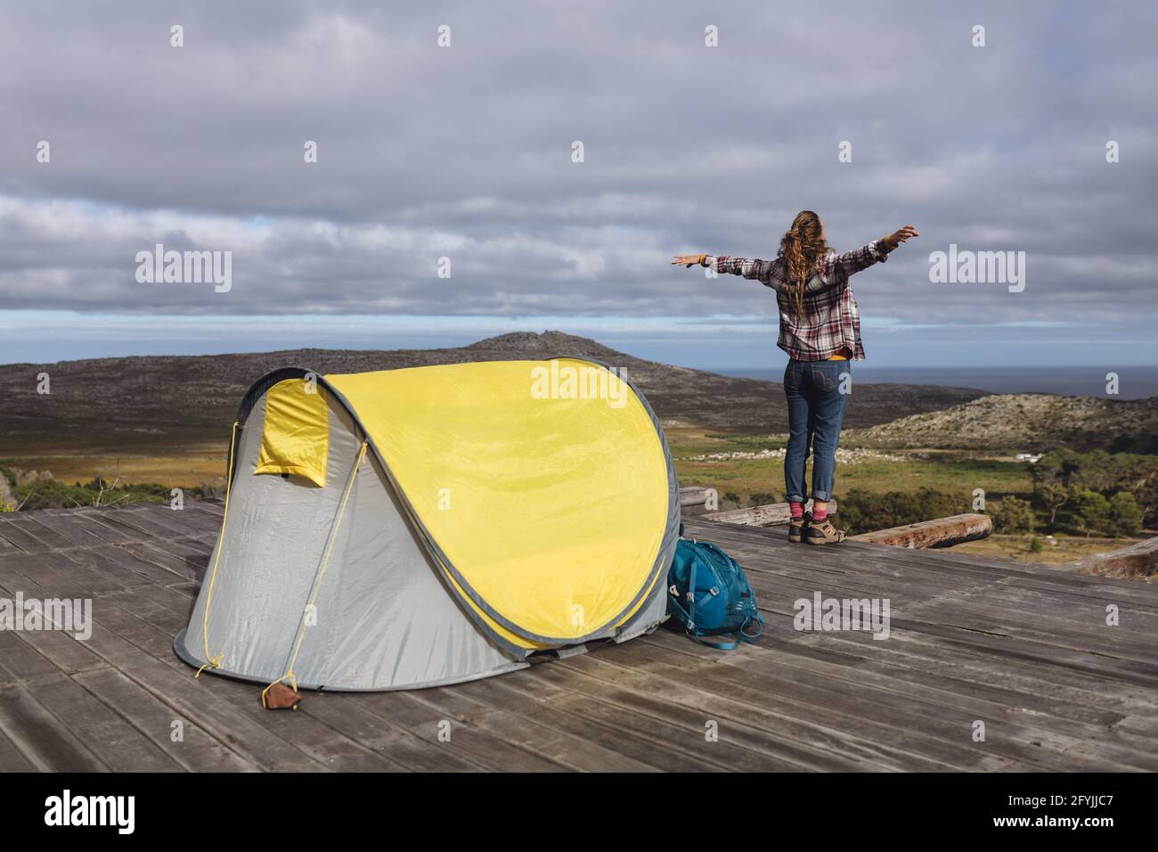 Rear view of caucasian woman camping, standing outside tent on ...