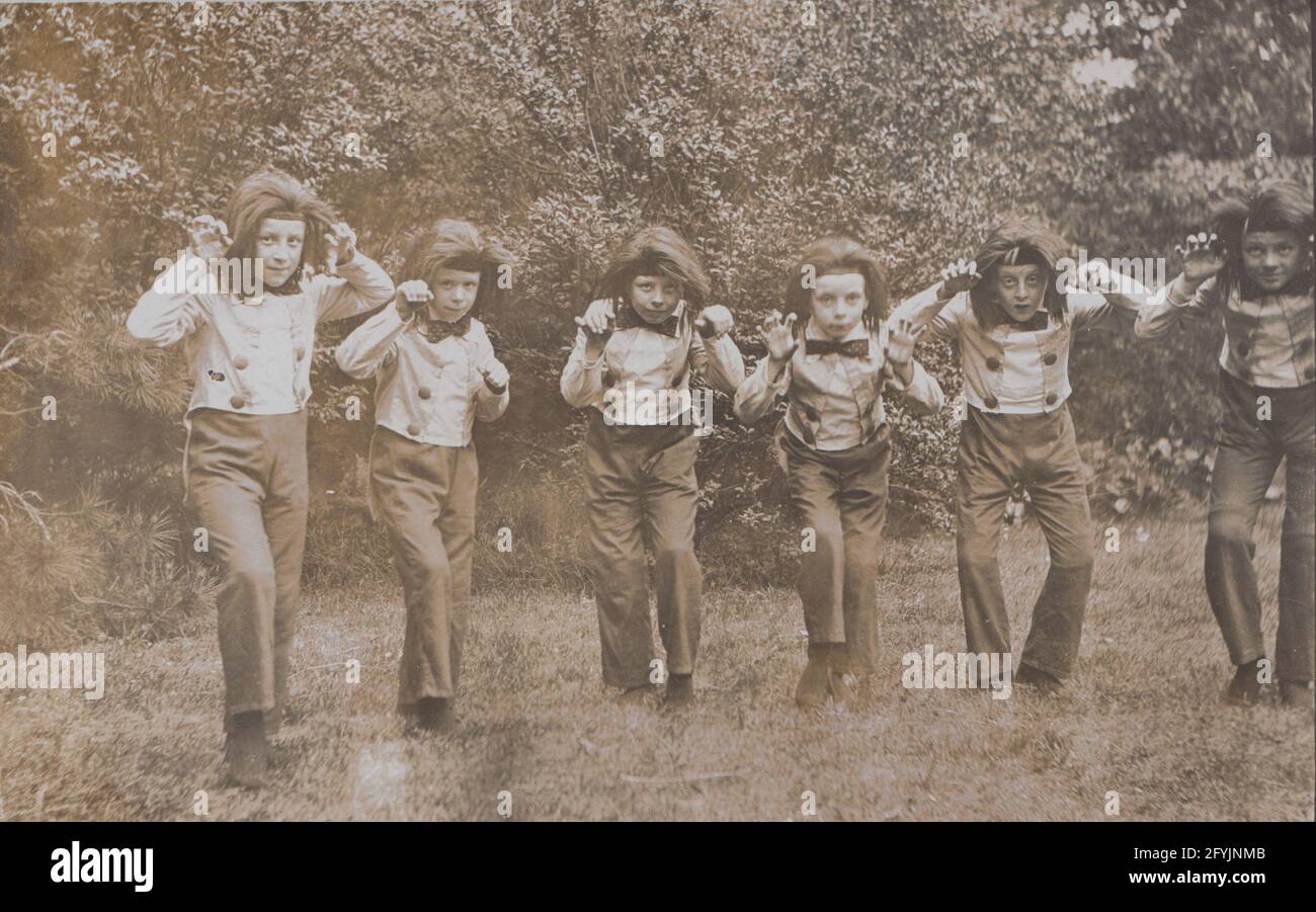 Group of six boys wearing theatrical costume and wearing the same wigs ...
