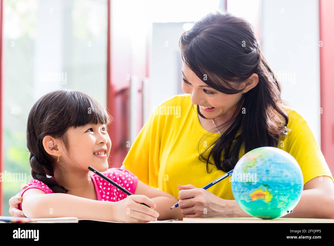 Chinese mother doing school homework with child or homeschooling ...