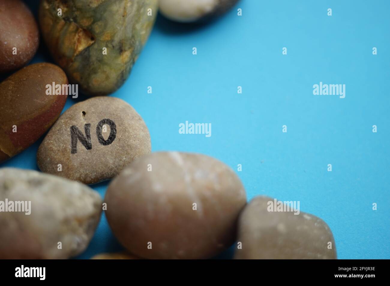 Pebble stone with the text no on blue table in a heap of clean pebbles ...