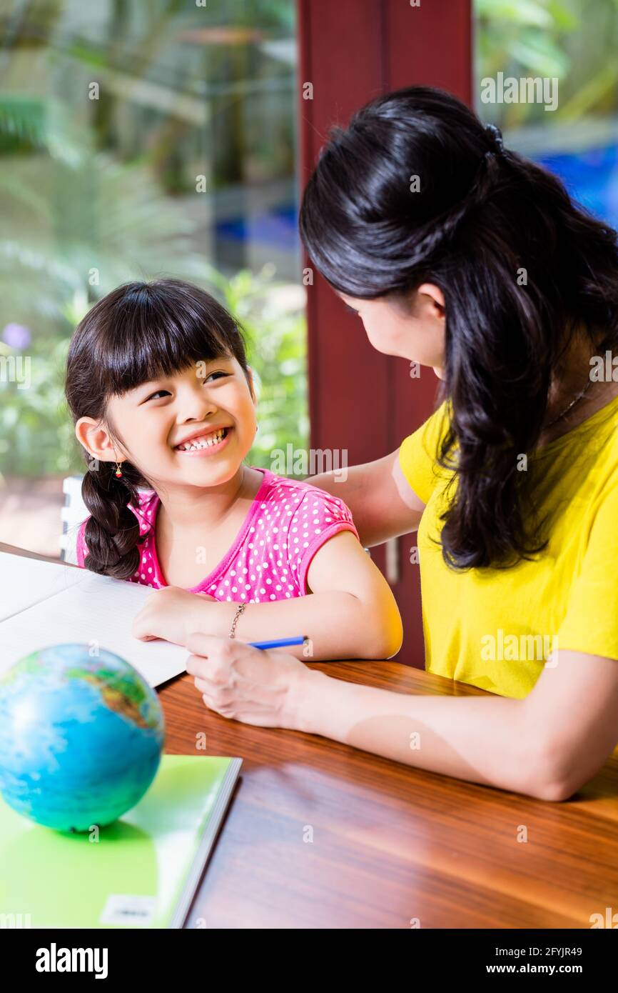 Chinese mother doing school homework with child or homeschooling ...