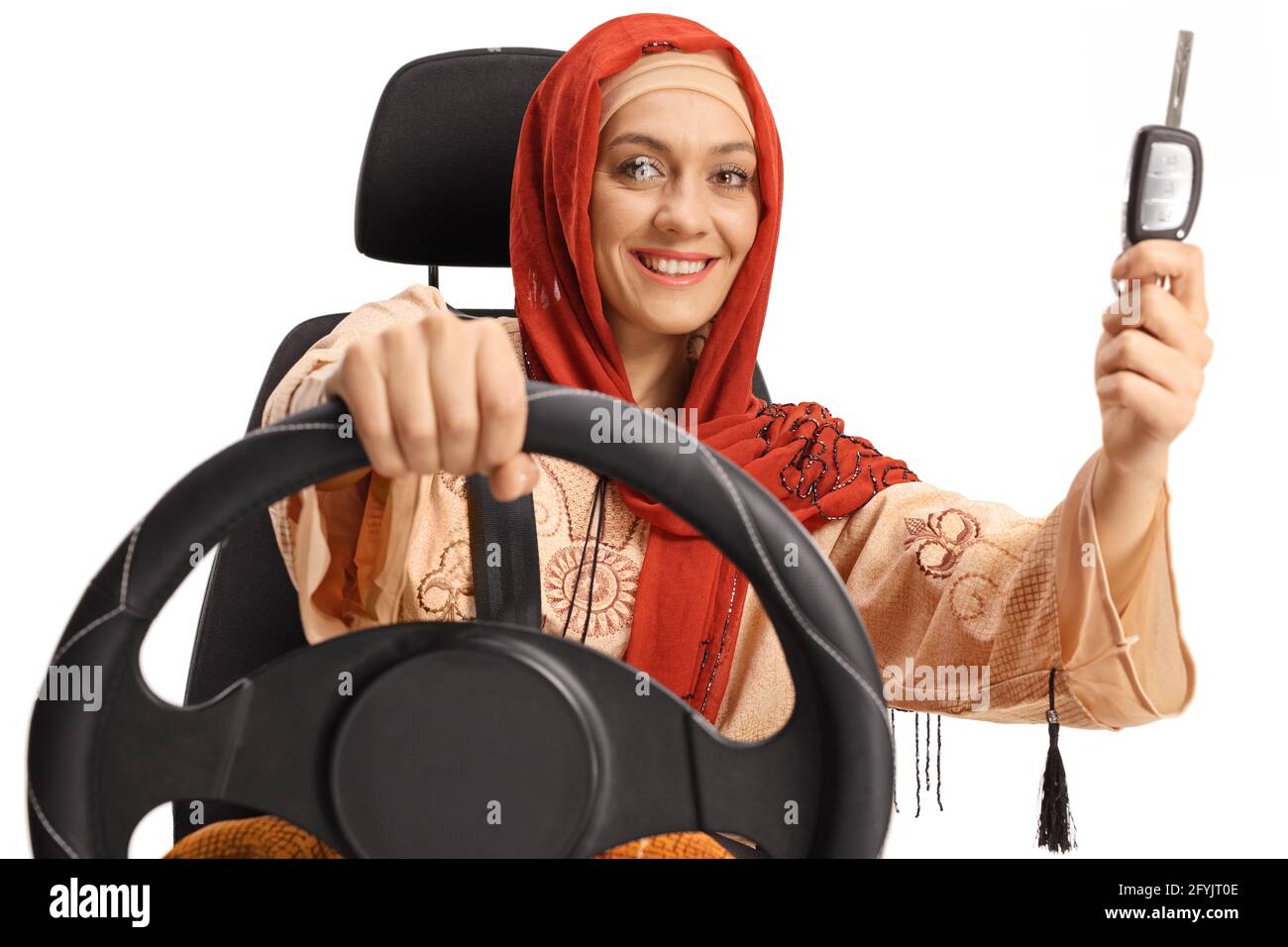 Muslim female driver in a car seat holding a key isolated on white ...