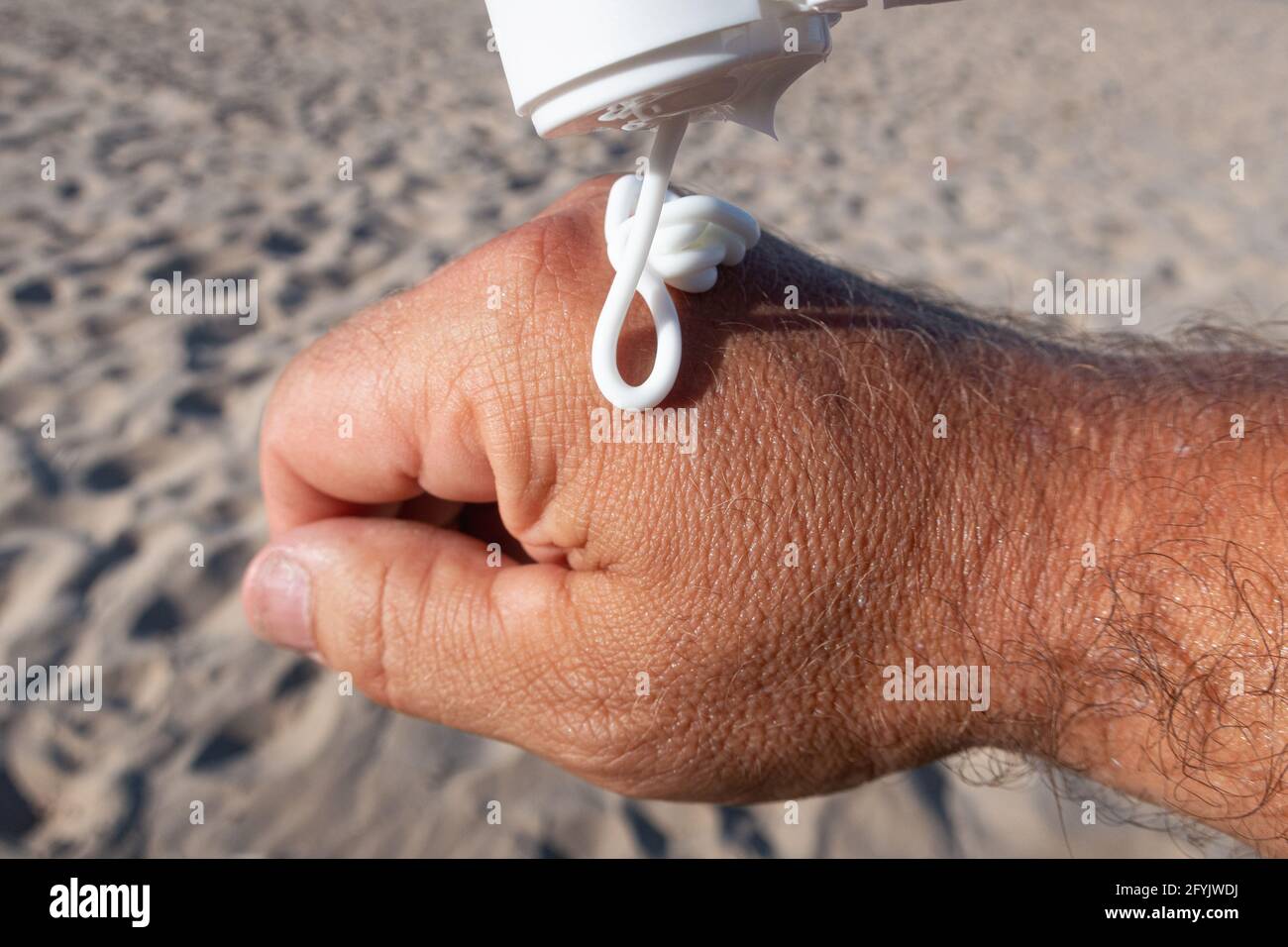 Man applying sunscreen cream to his hands on the beach Stock Photo - Alamy