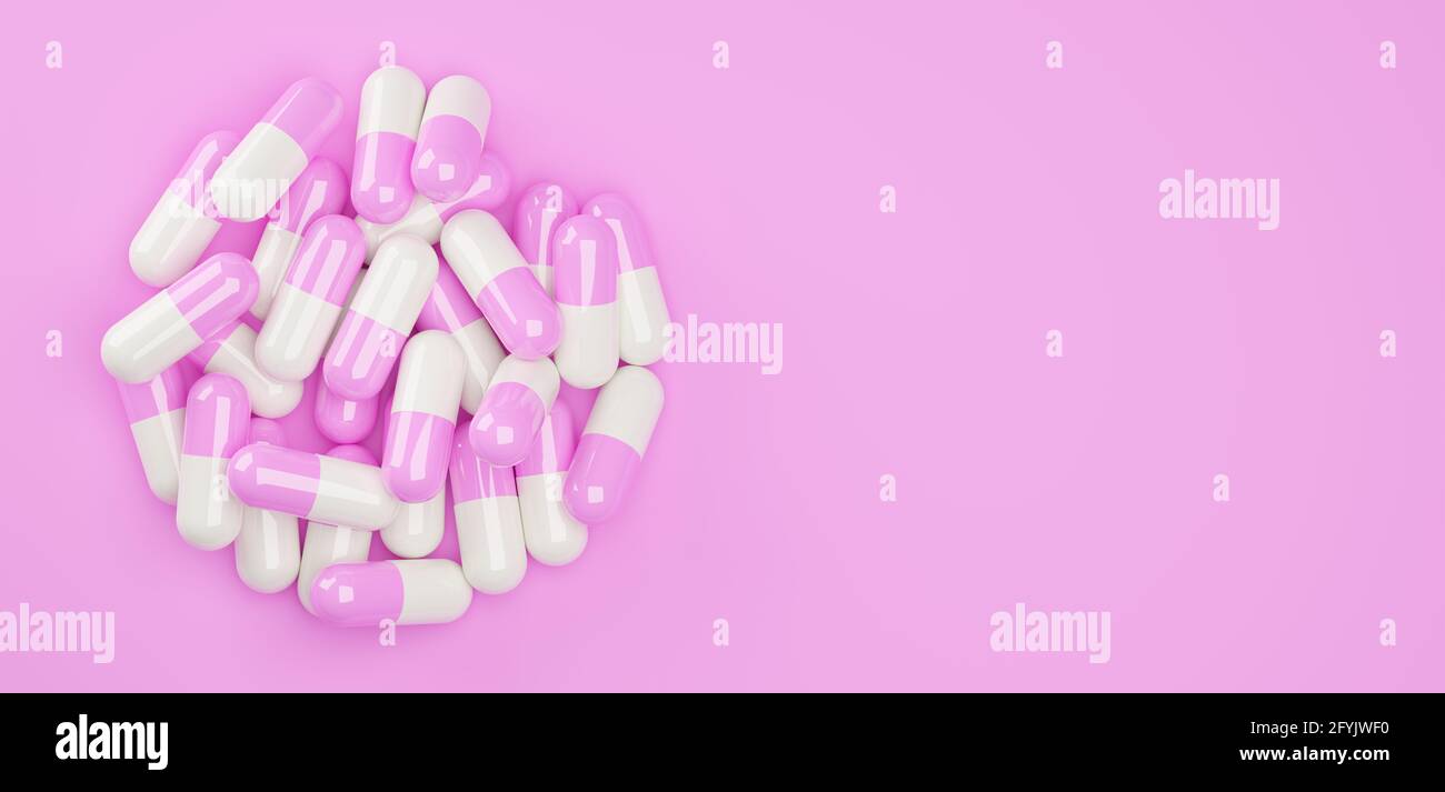 Pink and white pill capsules heap over pink background, female medical ...