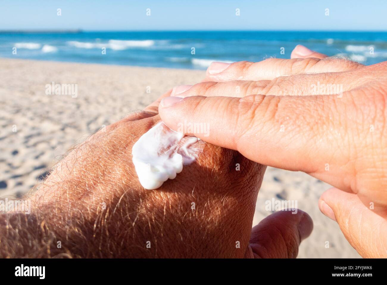 Man applying sunscreen cream to his hands on the beach Stock Photo - Alamy