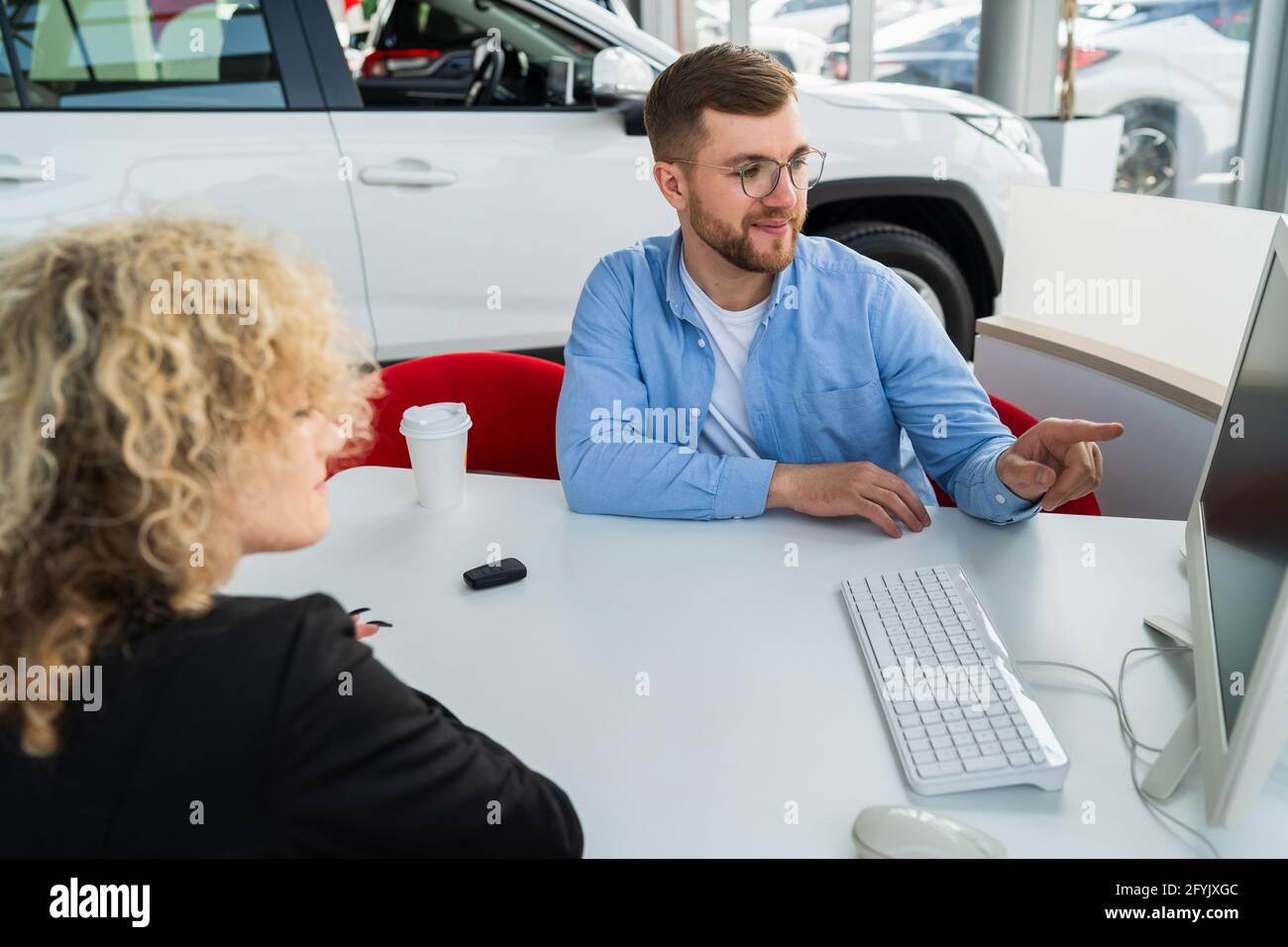 Car dealership manager with client at computer in showroom Stock Photo ...