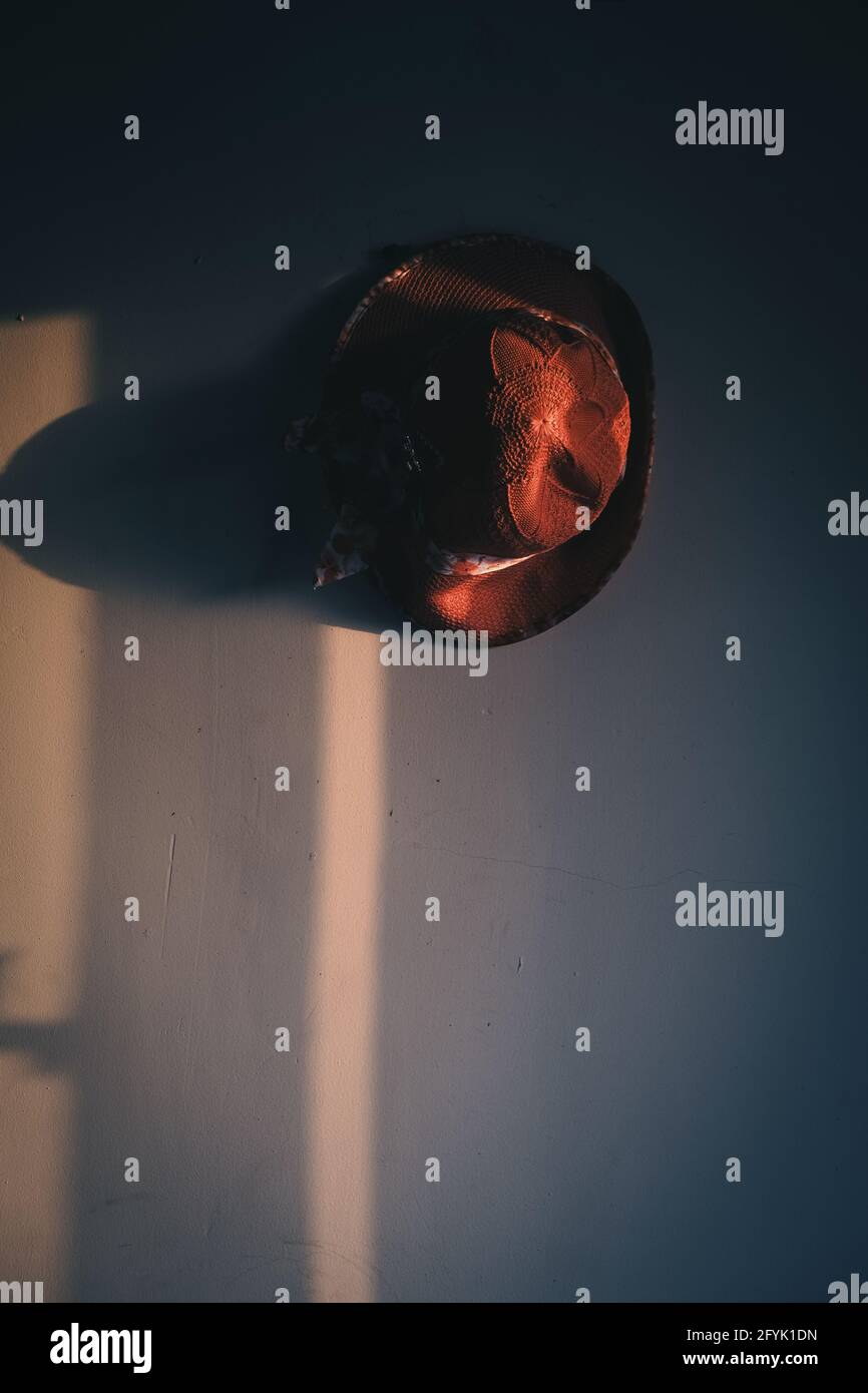 Vertical shot of a cowboy hat hung on the wall with sunlight falling on ...