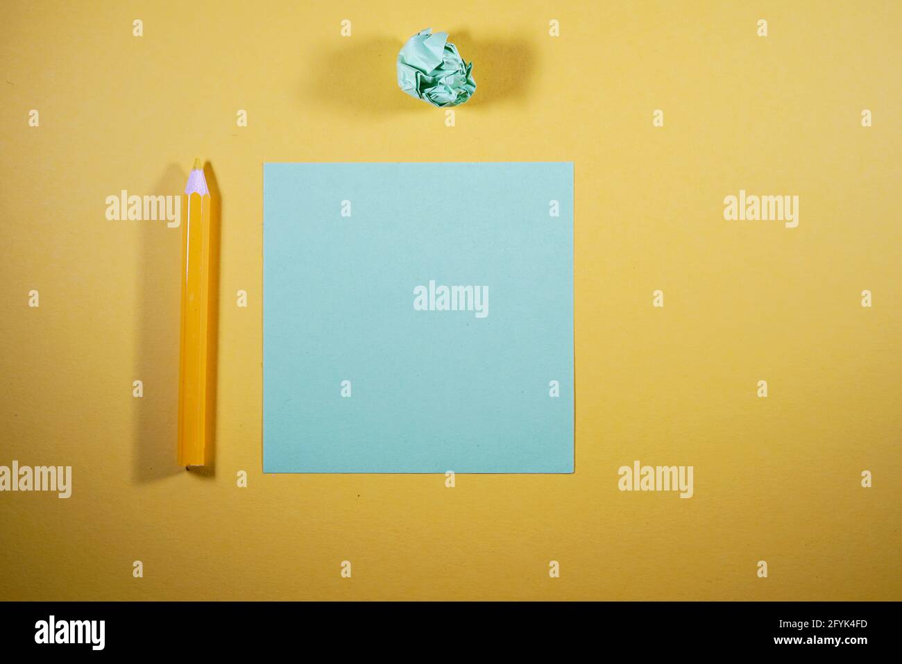 Flat lay of a waste paper ball, thick yellow pencil, and blank paper on ...