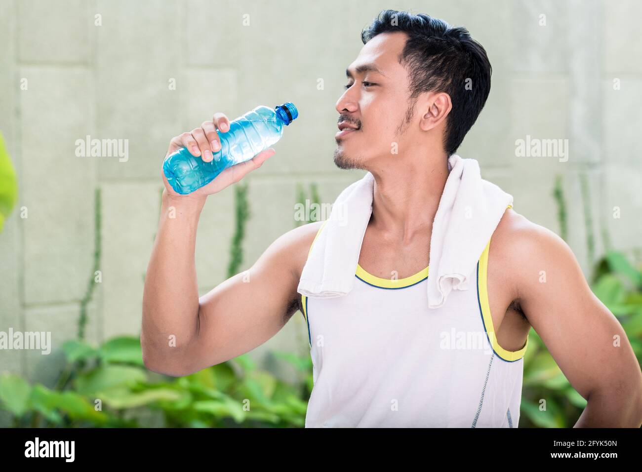 Asian man working out in his garden drinking water Stock Photo - Alamy