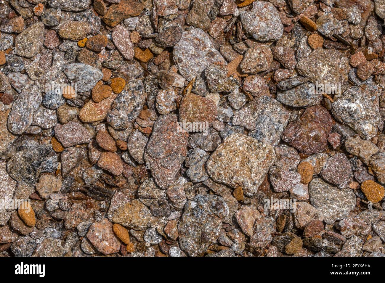 Looking down on a variety of shiny colorful rocks closeup laying on the ...
