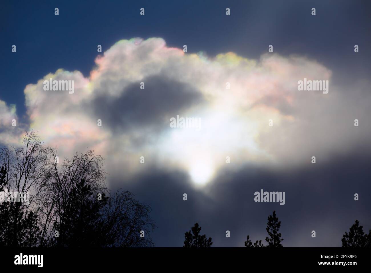 Sun behind rainbow colored clouds in April Stock Photo - Alamy